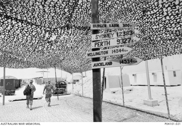 Two Australian service personnel walk past a sign post pointing out the ...