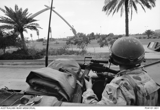 As an Australian Light Armoured Vehicle (ASLAV) passes by, an ...