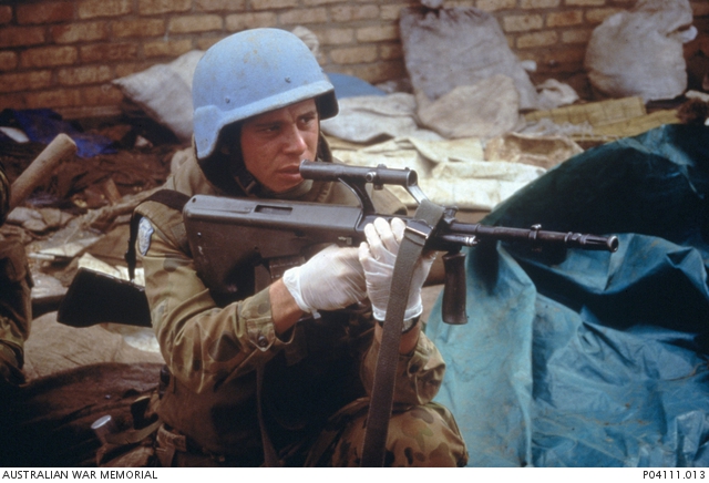 Private (Pte) Paul Burke, aiming his Styer rifle in the direction from ...