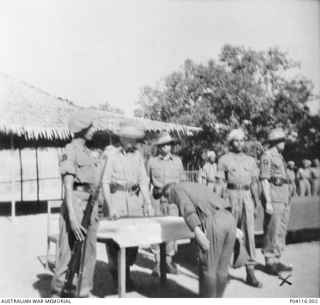 A Japanese Colonel having handed over his sword to a British Lieutenant ...