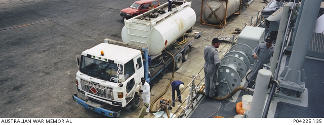 Refuelling HMAS Diamantina in Honiara harbour. A local refuelling truck ...