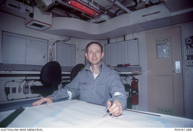 Portrait of Captain (Capt) Peter Jones, AM, RAN, holding a pair of ...