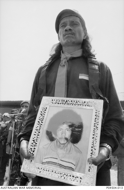 A member of the Aitarak militia holds a framed photograph of fellow ...