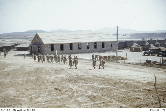 A group of soldiers moving toward a partially constructed building ...