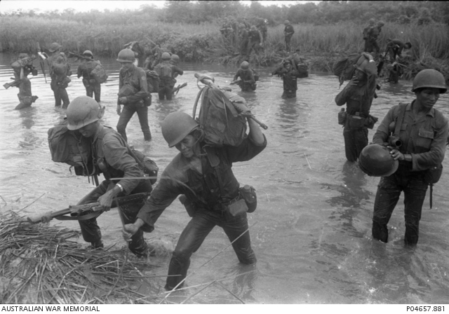 Carrying their packs on their shoulders, two soldiers from 3/52 ...