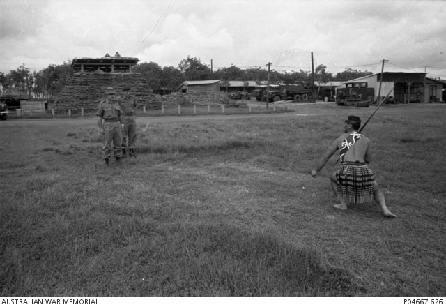 Dressed in traditional Maori ceremonial garb and armed with a spear, a ...