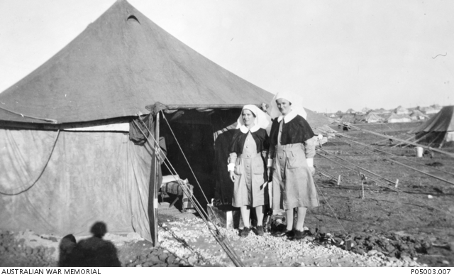 Informal portrait of two nursing sisters standing outside the tent they ...