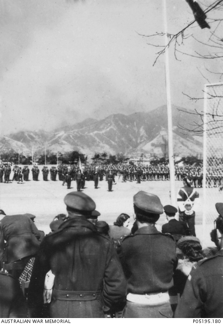 A crowd of officers and civilians watch a British Commonwealth ...