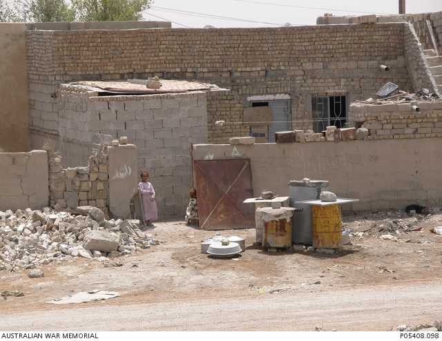 Two Iraqi children playing amongst the rubble outside their home ...