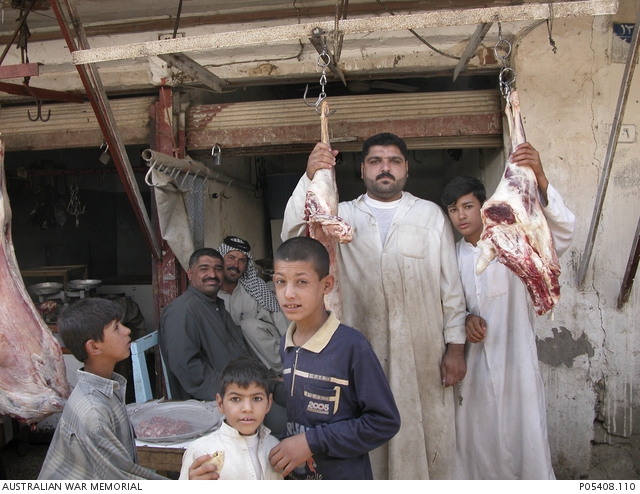 Local Iraqis standing outside their small butcher shop in a crowded ...