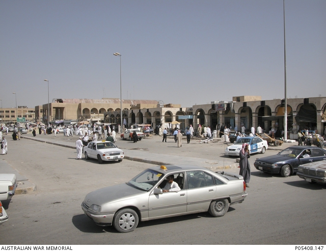 Iraqi civilians go about their business in a busy street in the town of ...