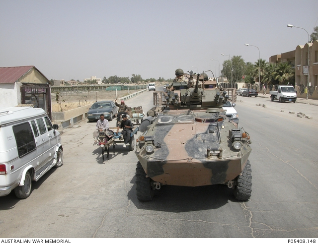 An Australian Light Armoured Vehicle (ASLAV) moving past cars and other ...