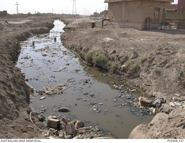 A polluted waterway, filled with debris and rubbish, in As Samawah ...
