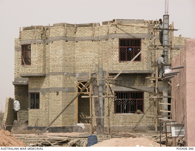 Iraqi construction workers working on a partially built house in As ...