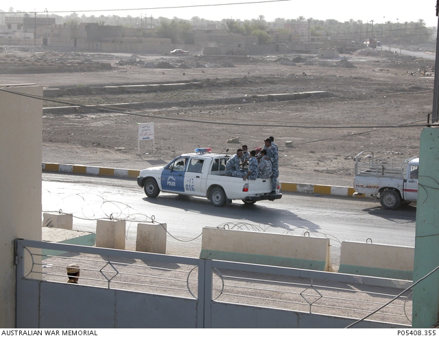 A number of Iraqi police officers in the back of a police vehicle as it ...