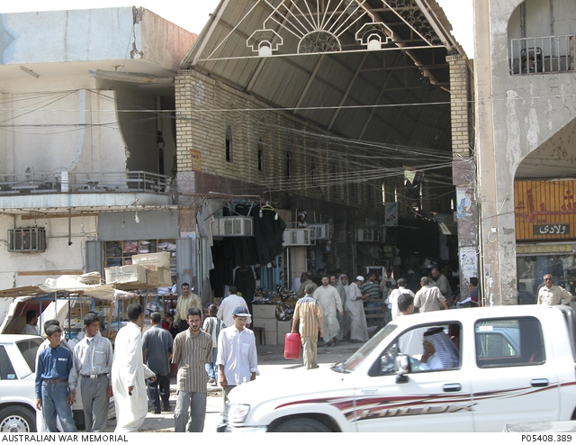 Iraqi locals streaming in and out of the entrance to a covered market ...
