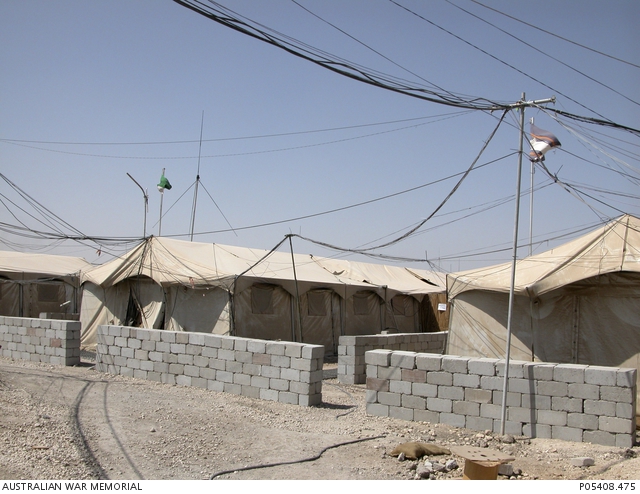 Unit flags flying over work tents at Camp Smitty. The tents are ...