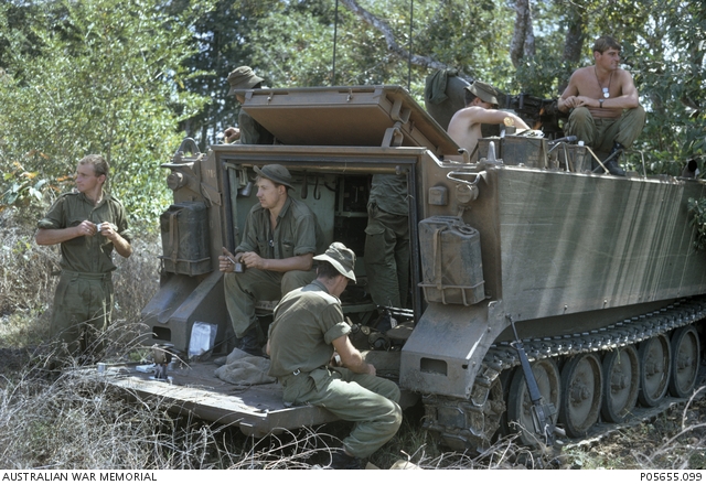 Australian soldiers eating from ration packs around their APC. Crouched ...