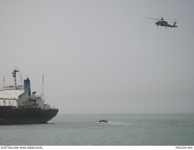 A RHIB and Navy Seahawk helicopter of HMAS Parramatta intercepting a ...