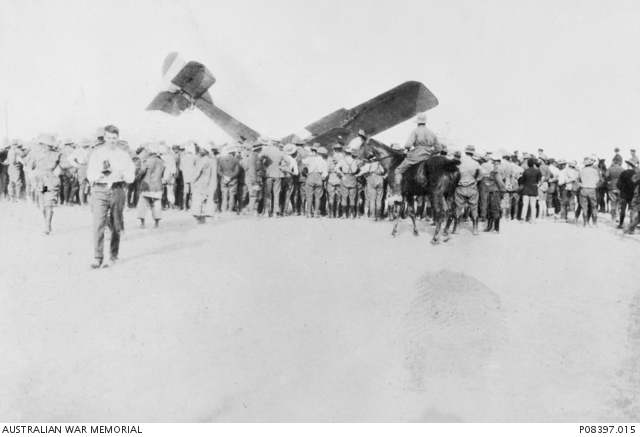 Members of the 2nd Light Horse Brigade crowd around a crashed biplane ...
