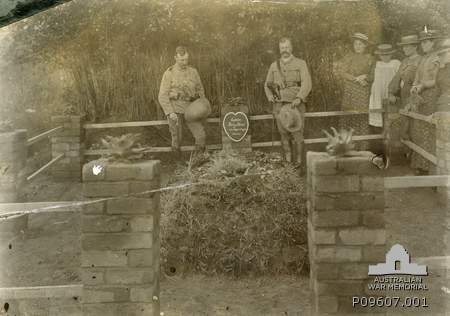 Two soldiers and a group of civilians stand by the grave of Captain ...