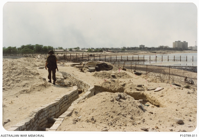 Australian soldier walking next to trench. the back of the photograph ...