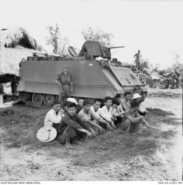 Sergeant W. G. (Jock) Wells of Sydney, NSW, stands guard over a group ...