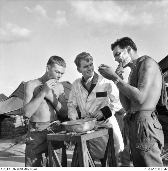 Vietnam. 1965-12. Three soldiers stand out in the open as they shave ...
