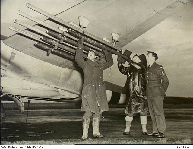 England. C. 1945-01. Airmen examine the rocket projectiles fitted to a ...