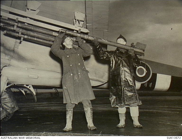 England. C. 1945-01. Airmen examine the rocket projectiles fitted to a ...