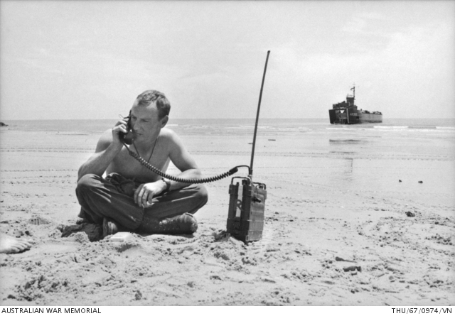 Vietnam. 1967-10. A radio operator sitting on a beach keeps in contact ...