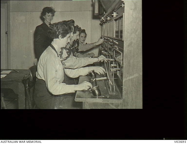 A WAAAF Corporal (rear) supervises a group of WAAAF telephonists at a ...