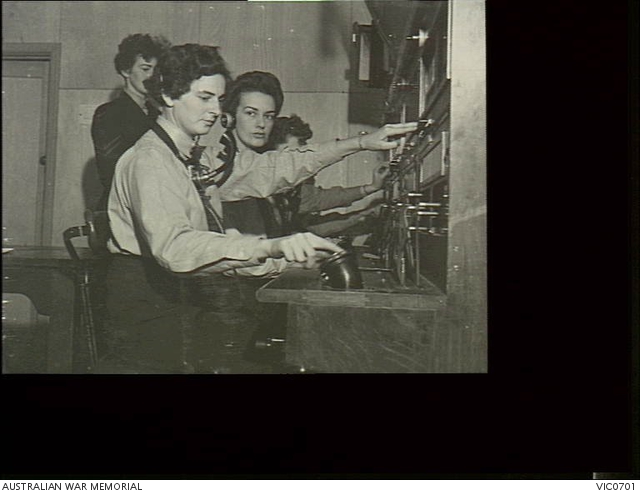 A WAAAF Corporal (rear) supervises a group of WAAAF telephonists at a ...